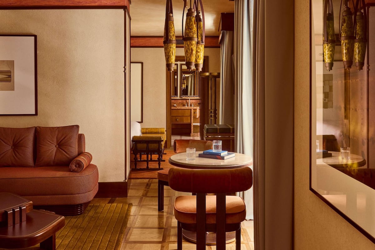 Um quarto aconchegante com um sofá de couro, uma mesa de centro de madeira e um espaço de jantar com uma cadeira e mesa.