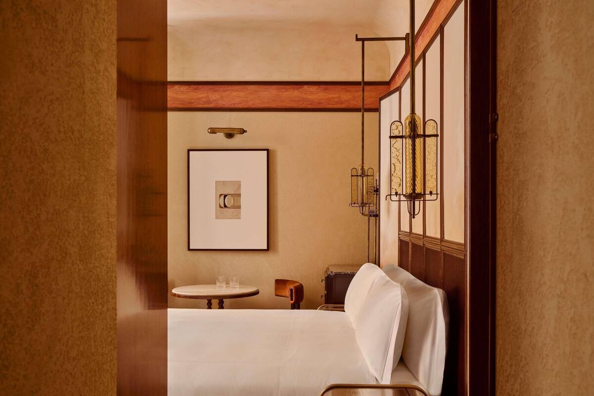 Quarto de hotel com cama, mesa de cabeceira e quadro na parede.