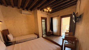 Quarto com duas camas, móveis de madeira e teto com vigas aparentes.