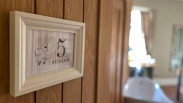 Placa emoldurada com o número 5, ilustração de um cão e o texto 'THE SILKIE' em uma parede de madeira.