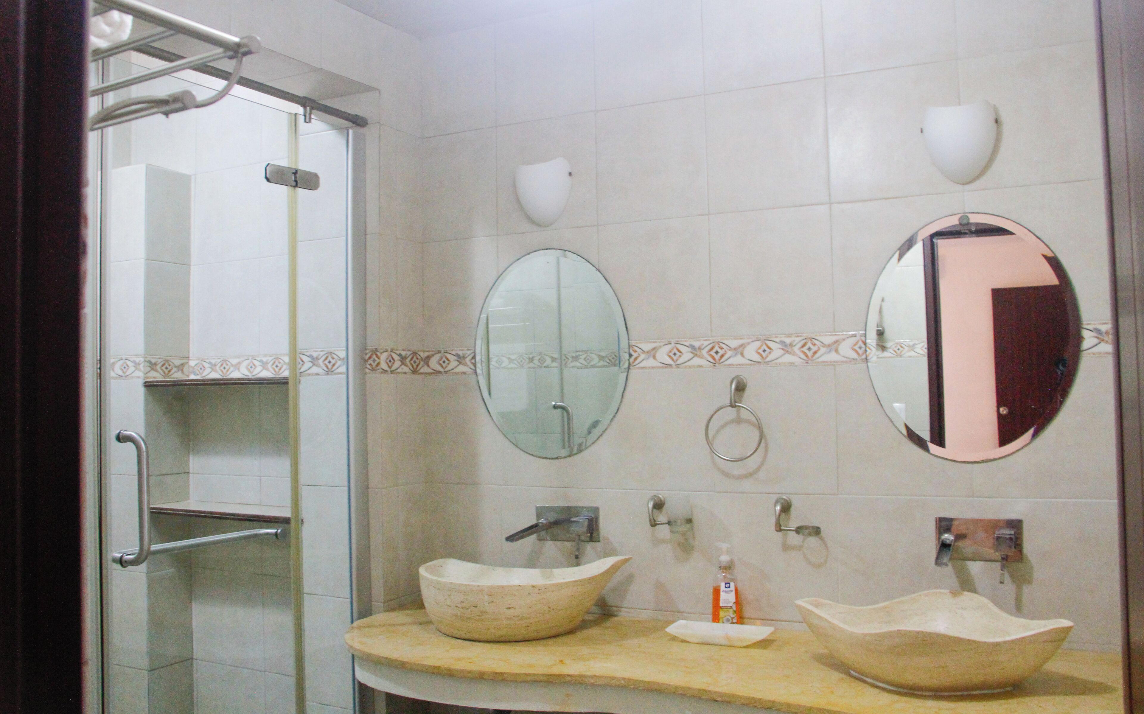 Casa de banho com duas pias, chuveiro e dois espelhos fixados na parede.