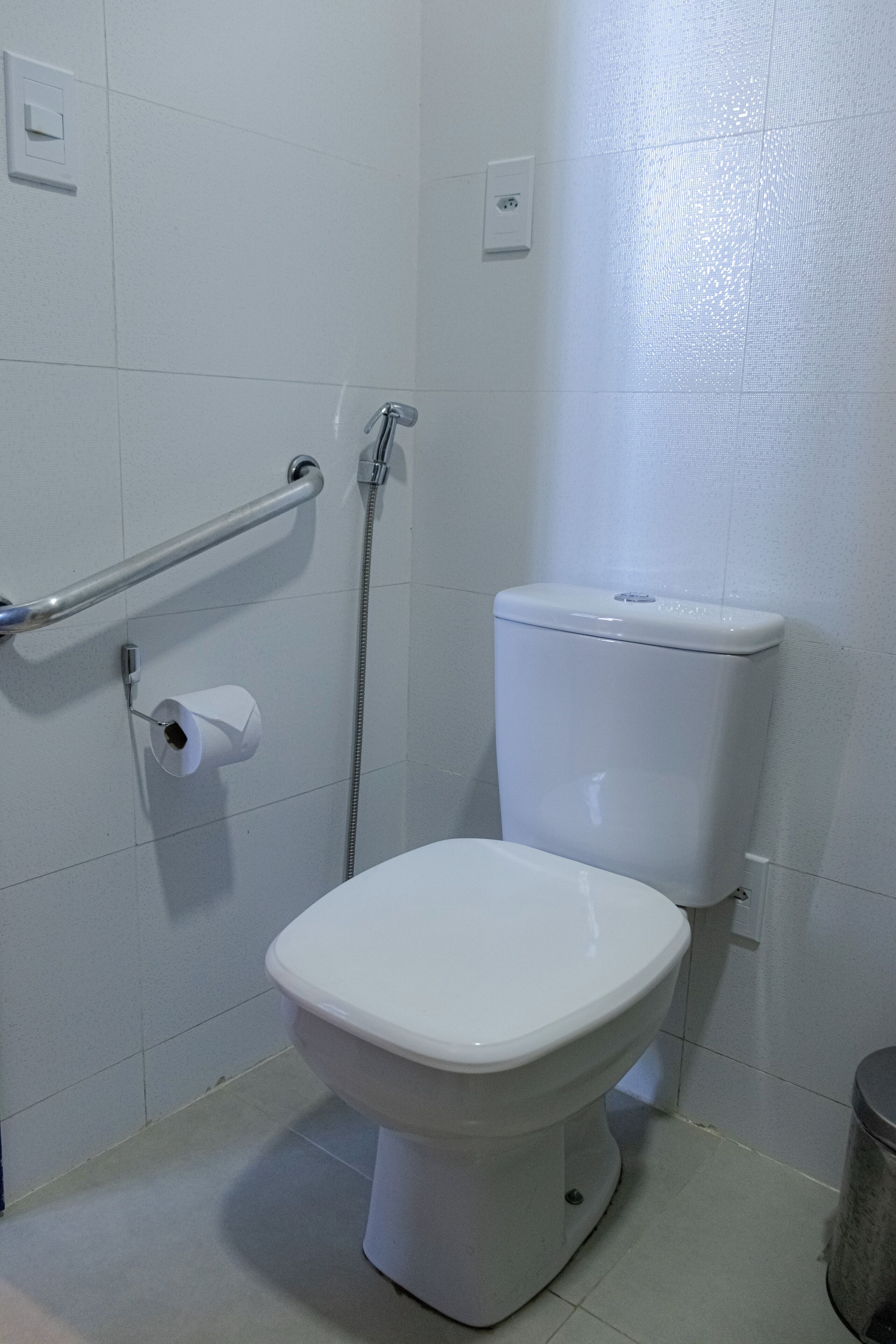 Sanita branca com função bidê, suporte para papel higiénico e barra de apoio.