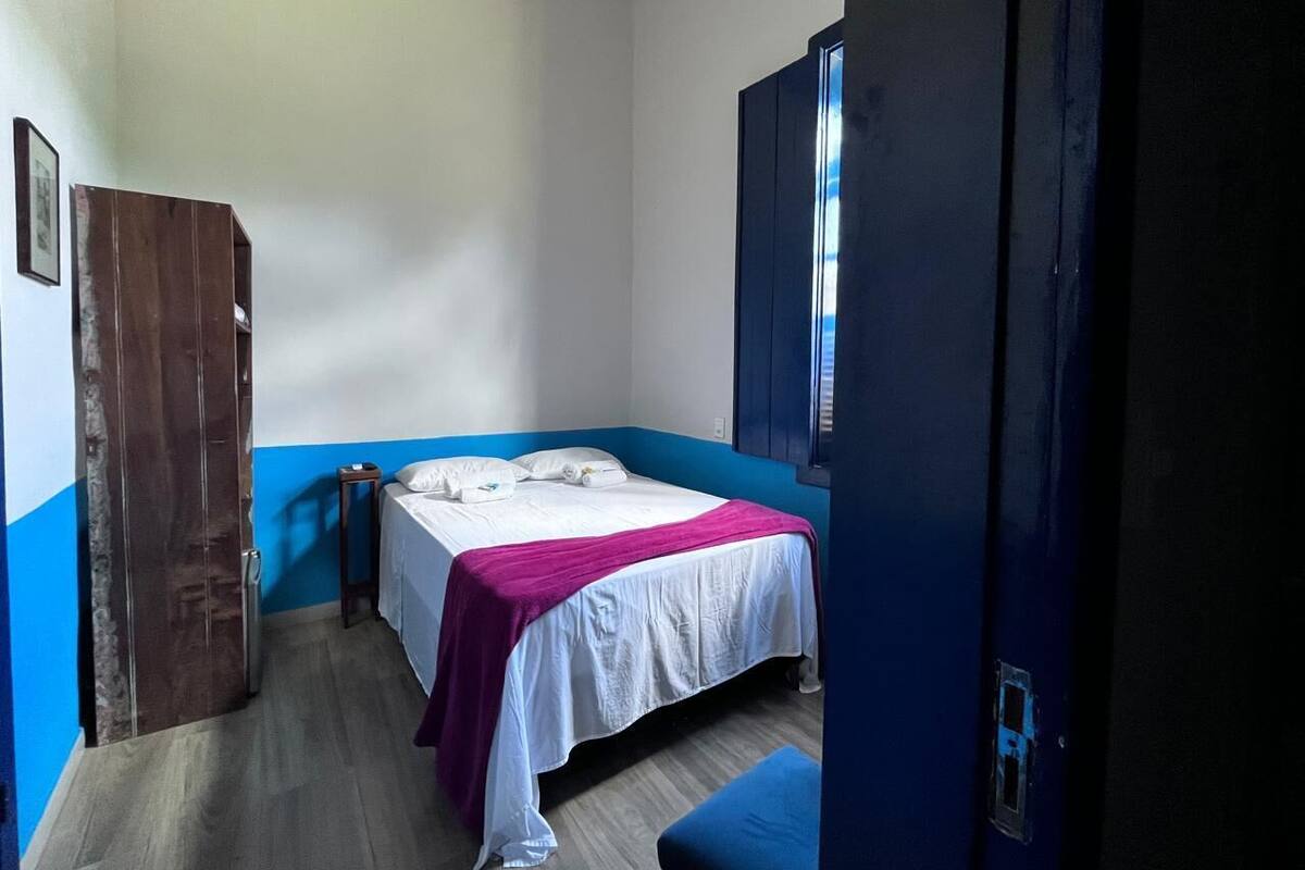 Um quarto com uma cama, uma porta de madeira e uma janela.
