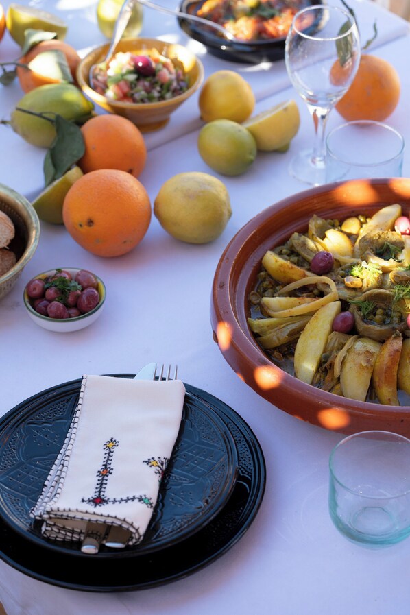 Uma mesa posta com uma variedade de frutas, uma salada em tigela, um prato de legumes e um guardanapo dobrado no prato.
