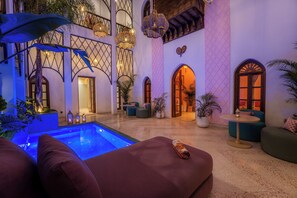Uma área de piscina interior luxuosa, com espaço para sentar, uma escadaria e vista para a piscina.