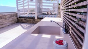 Um banheiro ao ar livre moderno com pia e cuba branca com flores vermelhas.