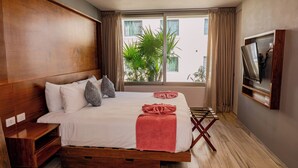 Quarto moderno com estrutura de cama de madeira, televisão fixada na parede e janela com cortinas.