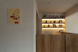 Uma cozinha moderna com armários de madeira, espaço para vinhos embutido e prateleira com objetos decorativos.