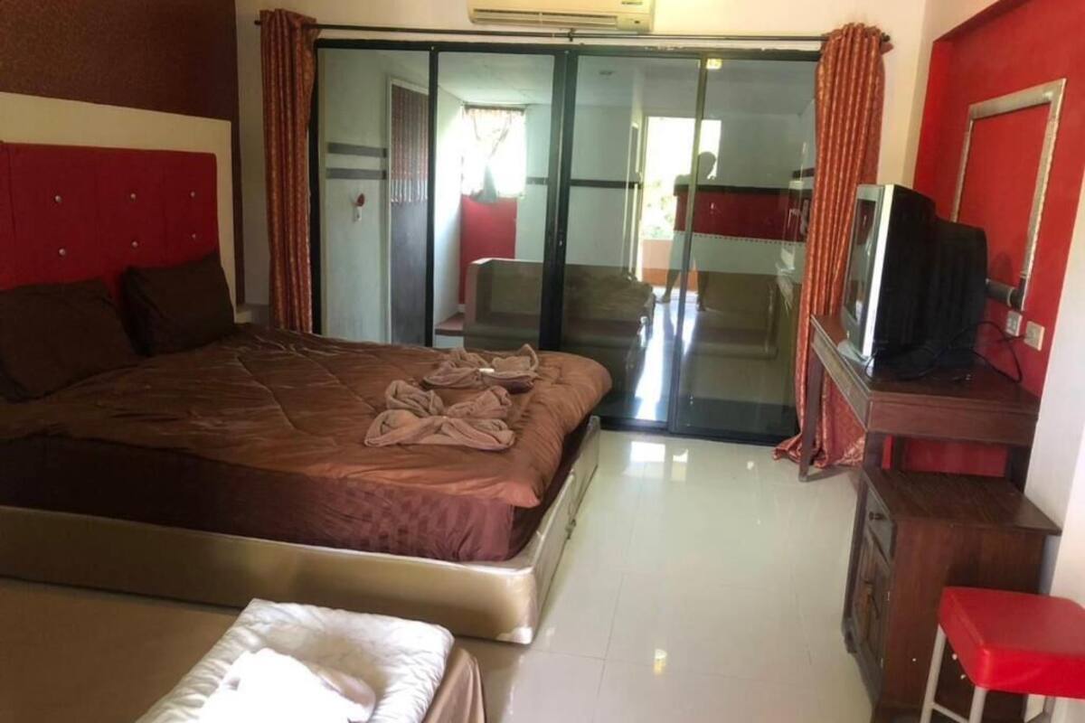 Quarto de hotel com cama, televisão, escrivaninha e cadeira.