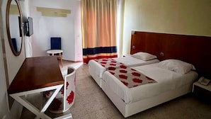 Quarto de hotel com cama, mesa de cabeceira, cadeira, escrivaninha e espelho.