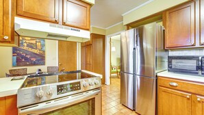 Cozinha com armários de madeira, eletrodomésticos de aço inoxidável e piso ladrilhado.