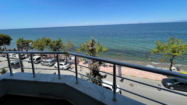Varanda com vista para o mar e carros estacionados.