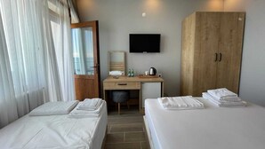 Quarto de hotel com duas camas, uma escrivaninha com espelho, televisão e guarda-roupa.