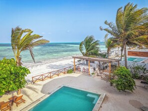 Na praia, areia branca, espreguiçadeiras, guarda-sóis 