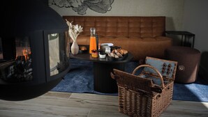Uma sala de estar acolhedora com lareira, um sofá, uma mesa de centro com lanches e uma cesta de vime.
