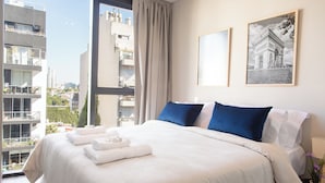 Quarto de hotel com uma cama grande, vista para a cidade e uma moldura na parede.