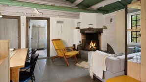 Um quarto aconchegante com lareira, uma mesa de madeira, um sofá e uma poltrona.