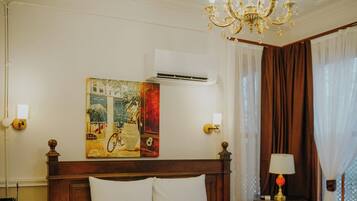 Quarto de hotel com cama de madeira, lustre, quadro na parede e mesa de cabeceira com luminária.