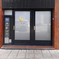 Fachada de edifício com entrada preta e porta de vidro exibindo um logotipo e o texto 'en part'.