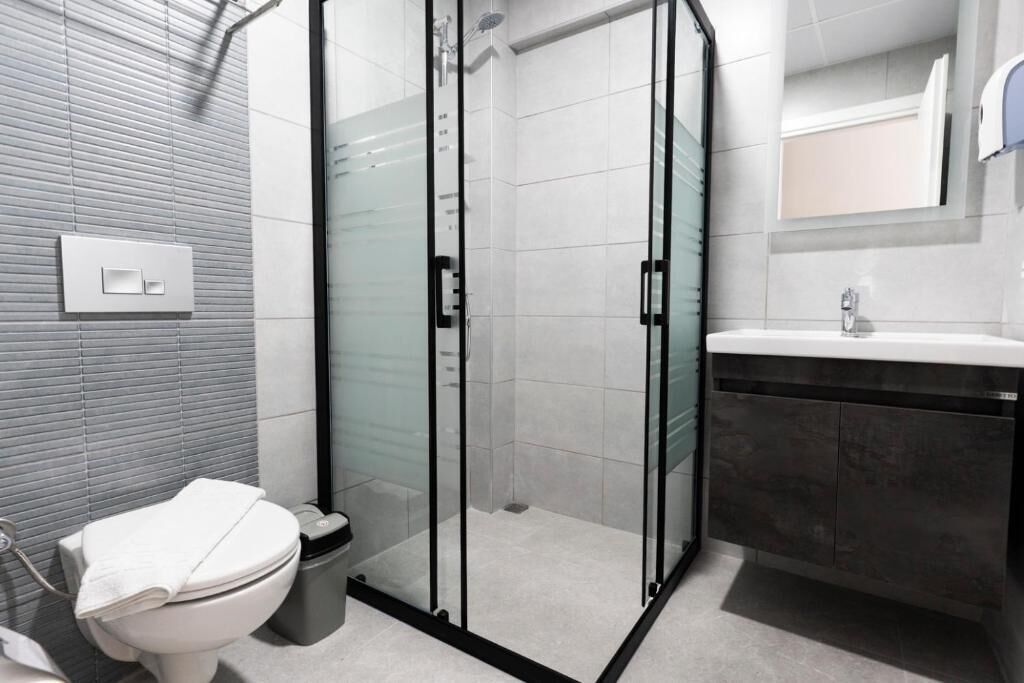 Uma casa de banho moderna com chuveiro de vidro, sanita e lavatório com espelho.