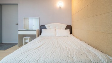 Quarto com cama, mesa de cabeceira, espelho e luminária na parede.