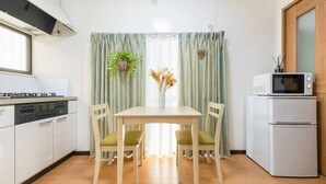 Uma cozinha compacta com mesa, cadeiras, micro-ondas e geladeira.