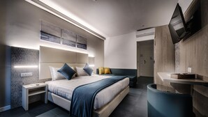 Quarto moderno com cama, mesas de cabeceira, televisão na parede e um banco embutido.