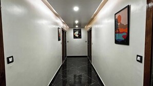 Um corredor com piso de mármore preto polido, paredes brancas e obras de arte nas paredes.