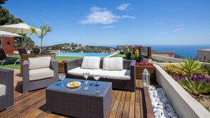Um terraço com mobiliário de vime, uma piscina e vista para o oceano.