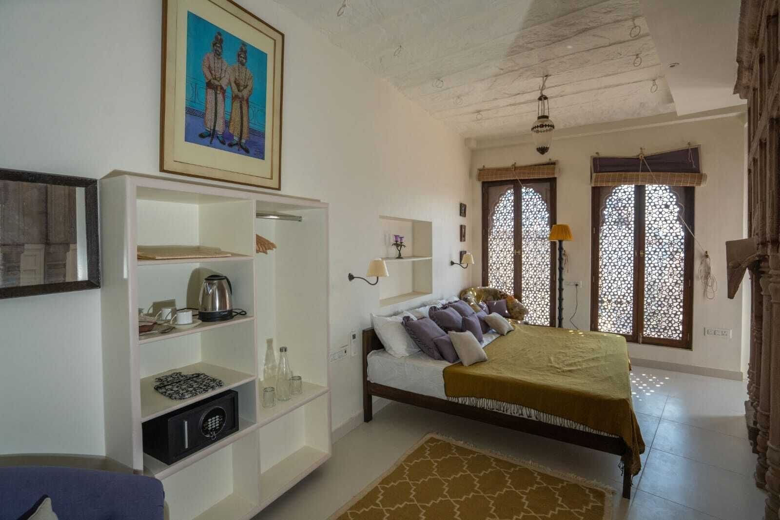 Quarto com cama, guarda-roupa, escrivaninha e janela com treliça decorativa.