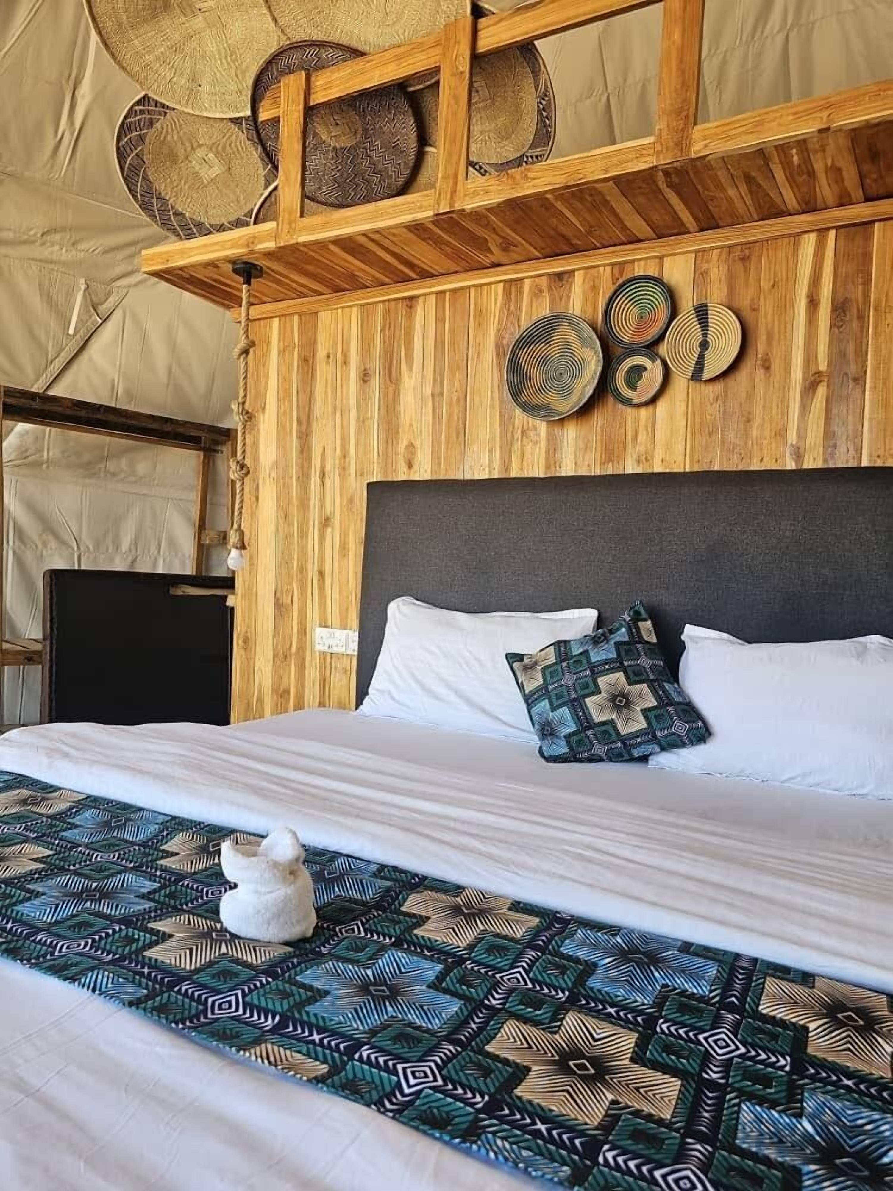 Cama com manta estampada, almofadas e objeto decorativo.