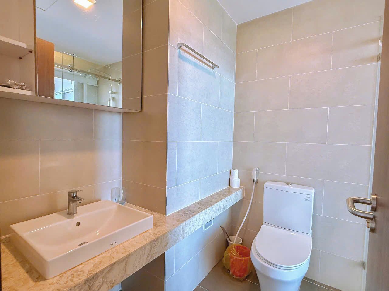 Casa de banho com lavatório, espelho, sanita e porta-toalhas.
