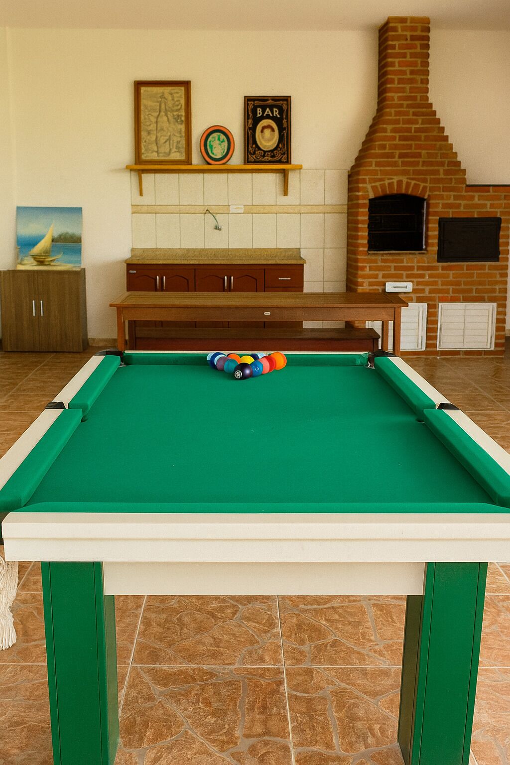 Uma mesa de bilhar com superfície de feltro verde, um banco de madeira e uma lareira de tijolos ao fundo.