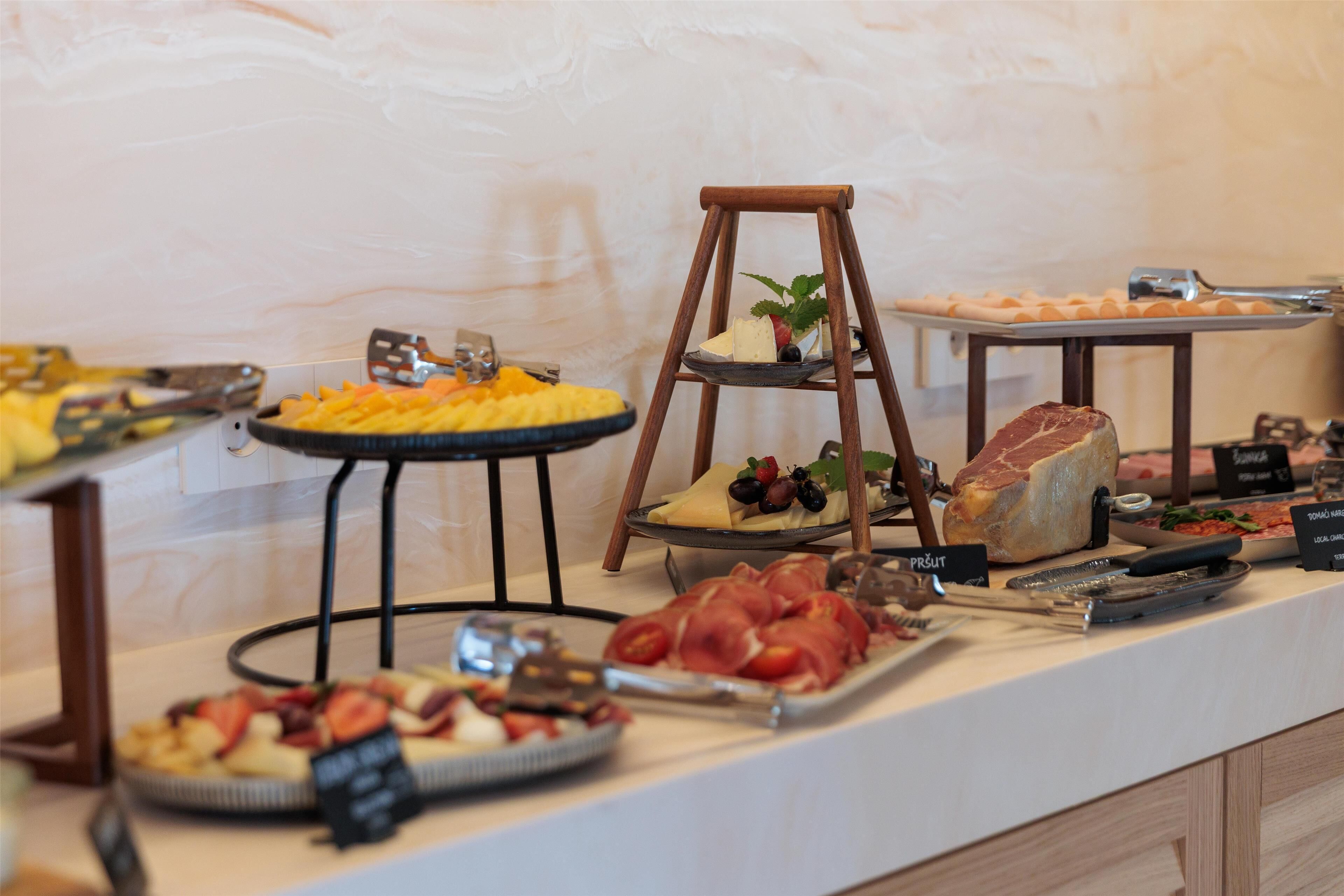 Buffet com diversos alimentos, incluindo frutas, queijos e carnes.