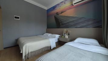 Quarto de hotel com duas camas, um quadro de um pôr do sol e um aparelho de ar condicionado.