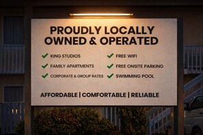 Um letreiro lista comodidades como Studios King, Apartamentos Familiares, Taxas para Empresas e Grupos, Wi-Fi Gratuito, Estacionamento Gratuito no Local e uma Piscina.