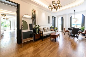Uma sala de estar ampla com piso de madeira, um sofá, uma mesa de centro e uma área de jantar com cadeiras e uma mesa.