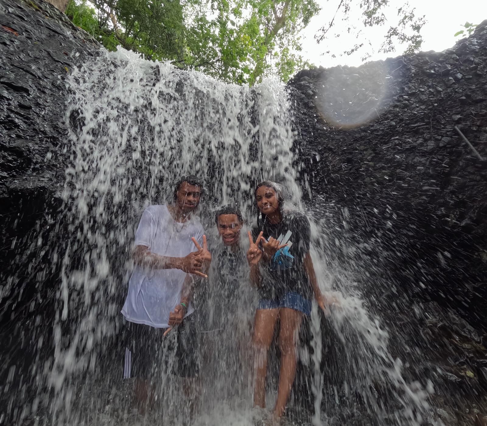 Uma cascata com três pessoas em frente.