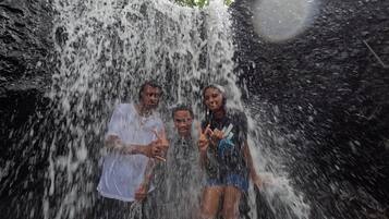 Uma cascata com três pessoas em frente.