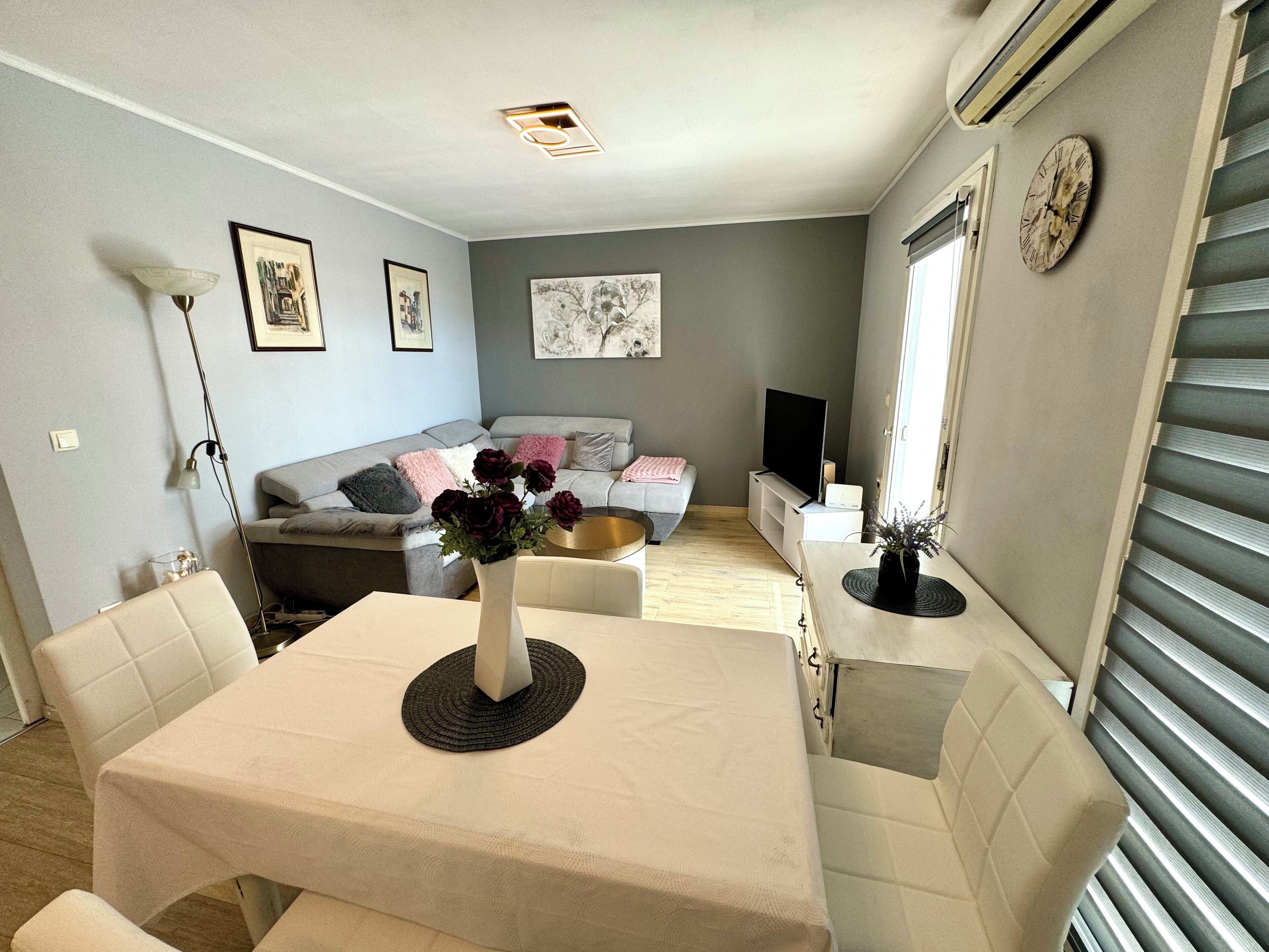 Uma sala de estar moderna com uma mesa de jantar, sofá e televisão.