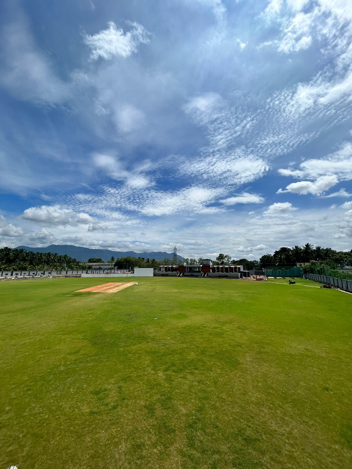 Um amplo campo gramado com um campo de beisebol, cercado por uma cerca e árvores.