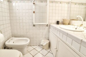 Casa de banho com sanita, bidé, lavatório e espelho.
