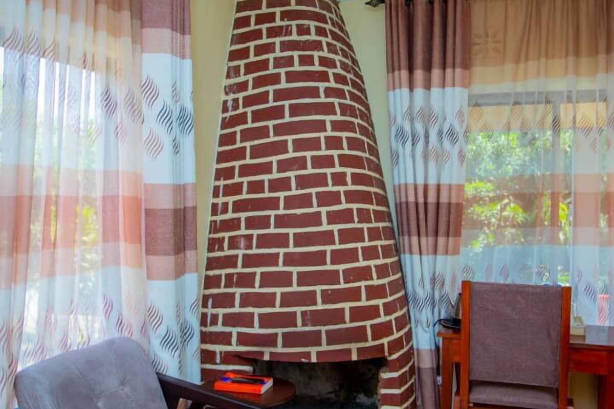 Uma sala de estar acolhedora com lareira de tijolos, duas poltronas e uma mesa.