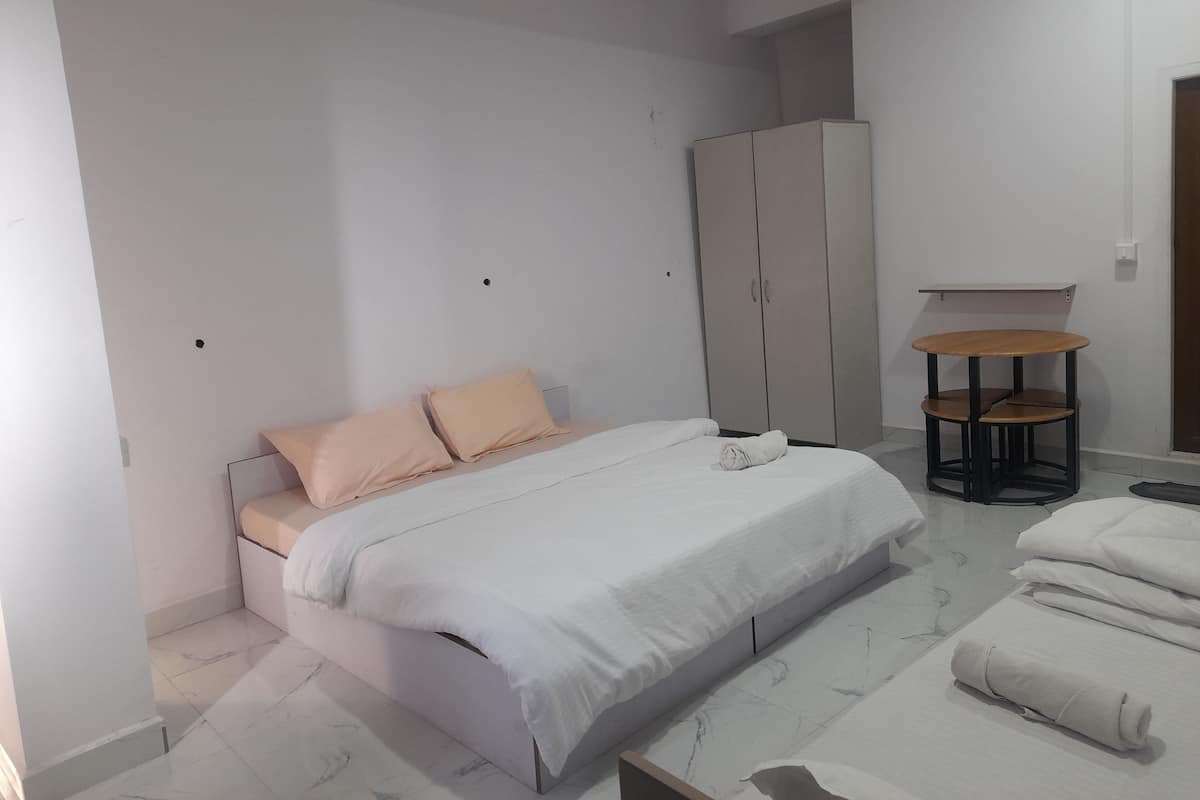 Um quarto minimalista com uma cama, um guarda-roupa e uma pequena mesa redonda.