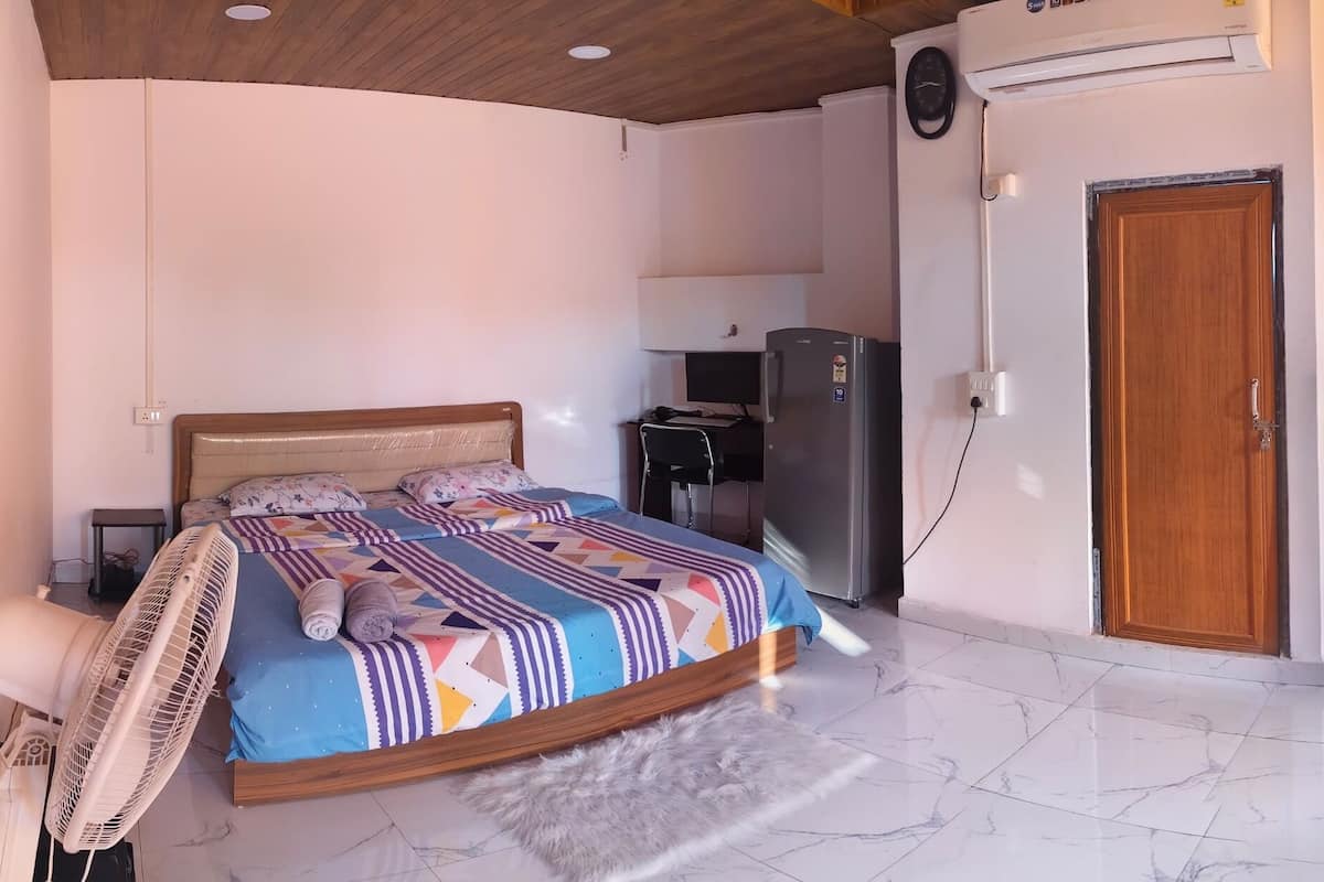 Quarto com cama, escrivaninha, sofá e mesa de jantar.