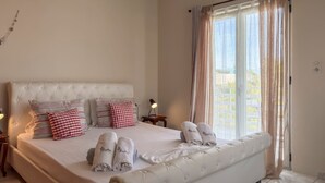 Cama bem arrumada com almofadas listradas e xadrez, abajur de cabeceira e toalhas sobre a cama.