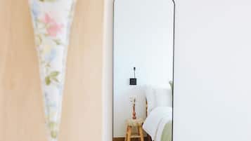 Quarto com uma cama, mesa de cabeceira, luminária e tomada na parede.