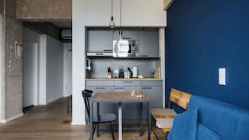 Cozinha moderna com micro-ondas, mesa de jantar, cadeiras e um sofá azul.