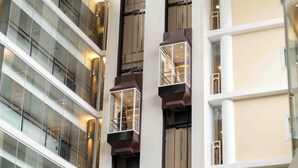 Edifício de vários andares com guarda-corpos de vidro e um eixo central para elevador.
