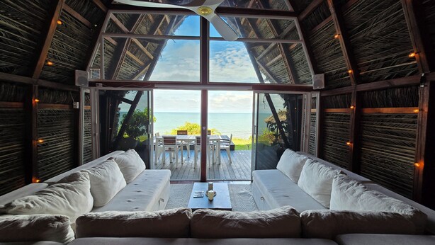 Quarto com uma grande porta de vidro que dá para uma varanda com vista para o mar.